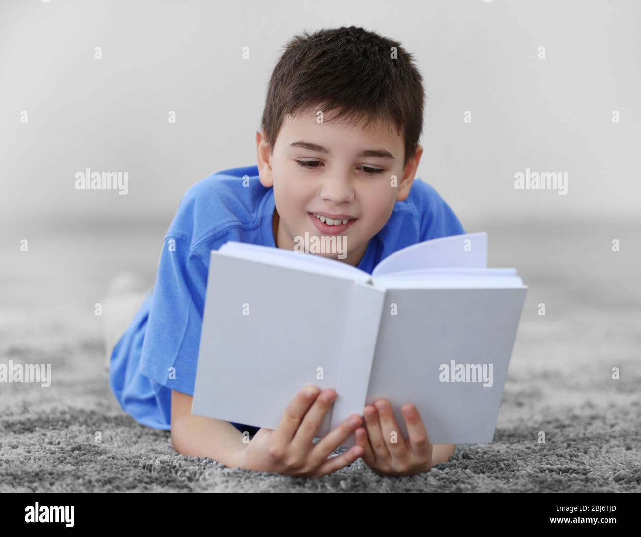 Little boy reading book on a floor at home Stock Photo - Alamy
