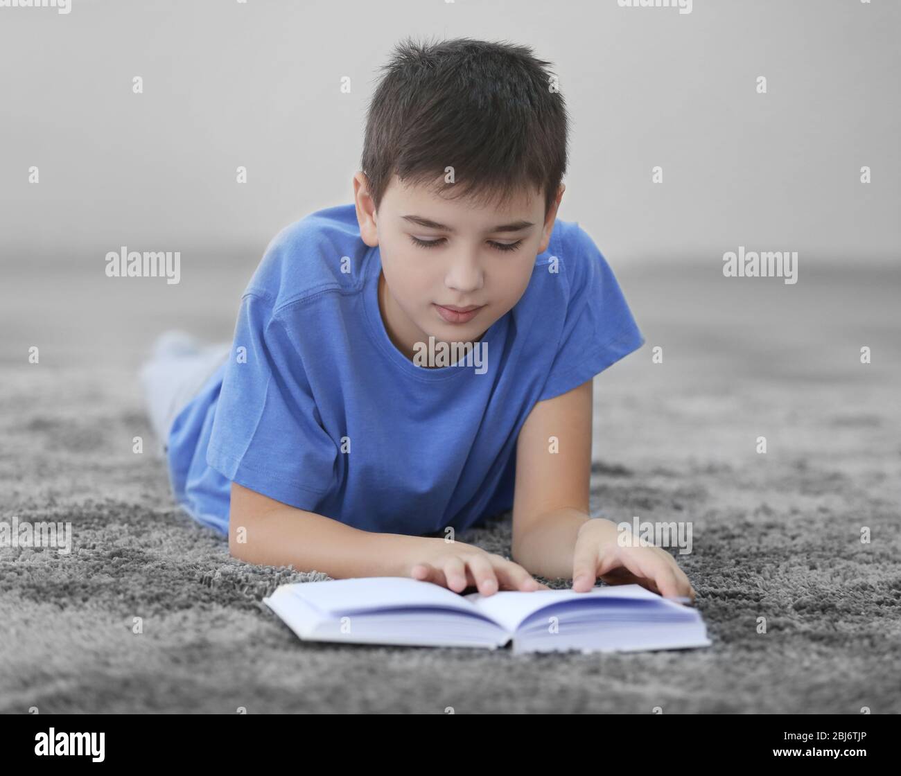 Little boy reading book on a floor at home Stock Photo - Alamy