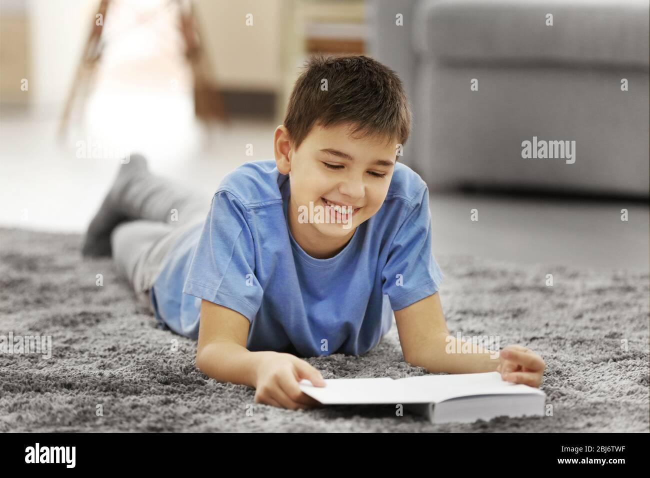 Boy reading book on a floor at home Stock Photo - Alamy