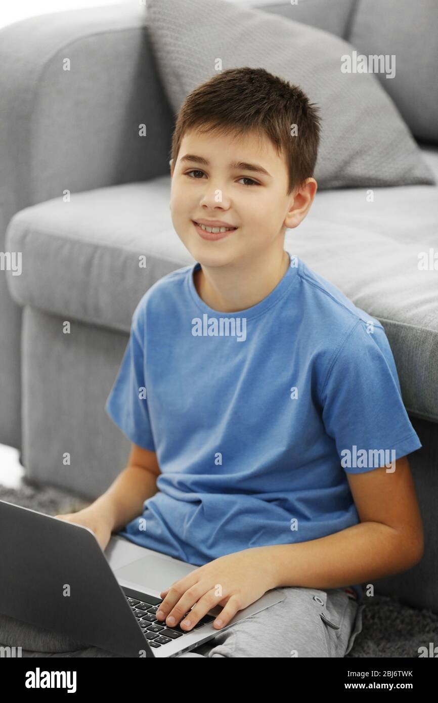 Boy with laptop sitting on a carpet at home Stock Photo - Alamy