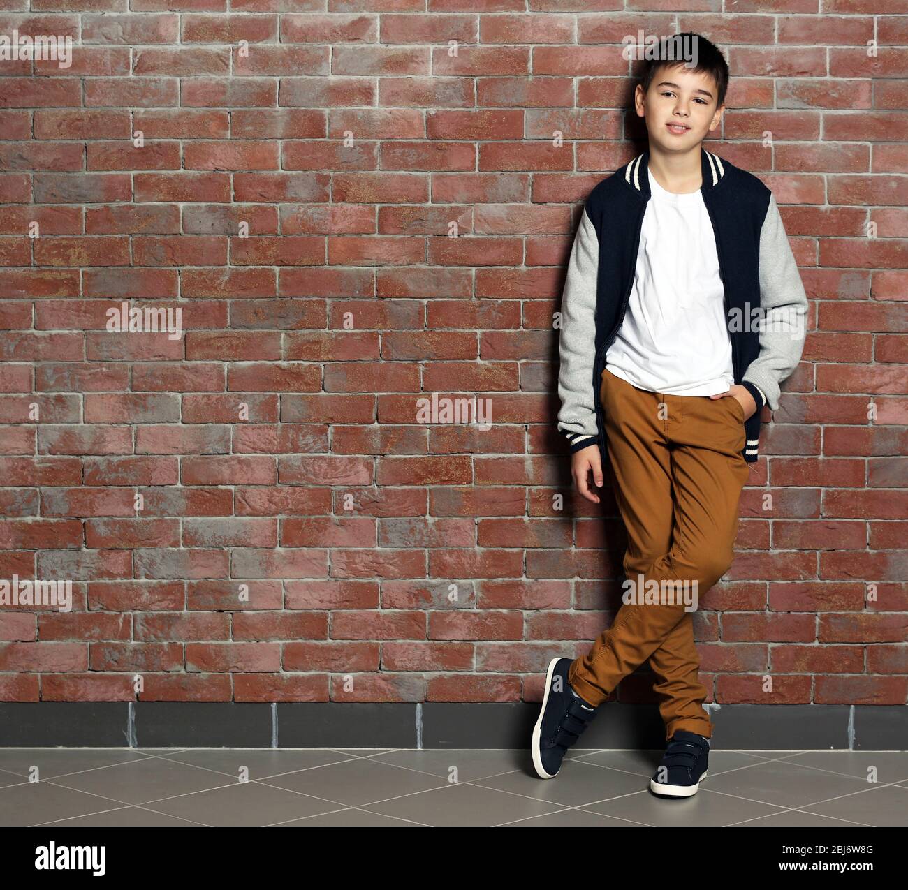 Cute little boy standing near brick wall Stock Photo - Alamy