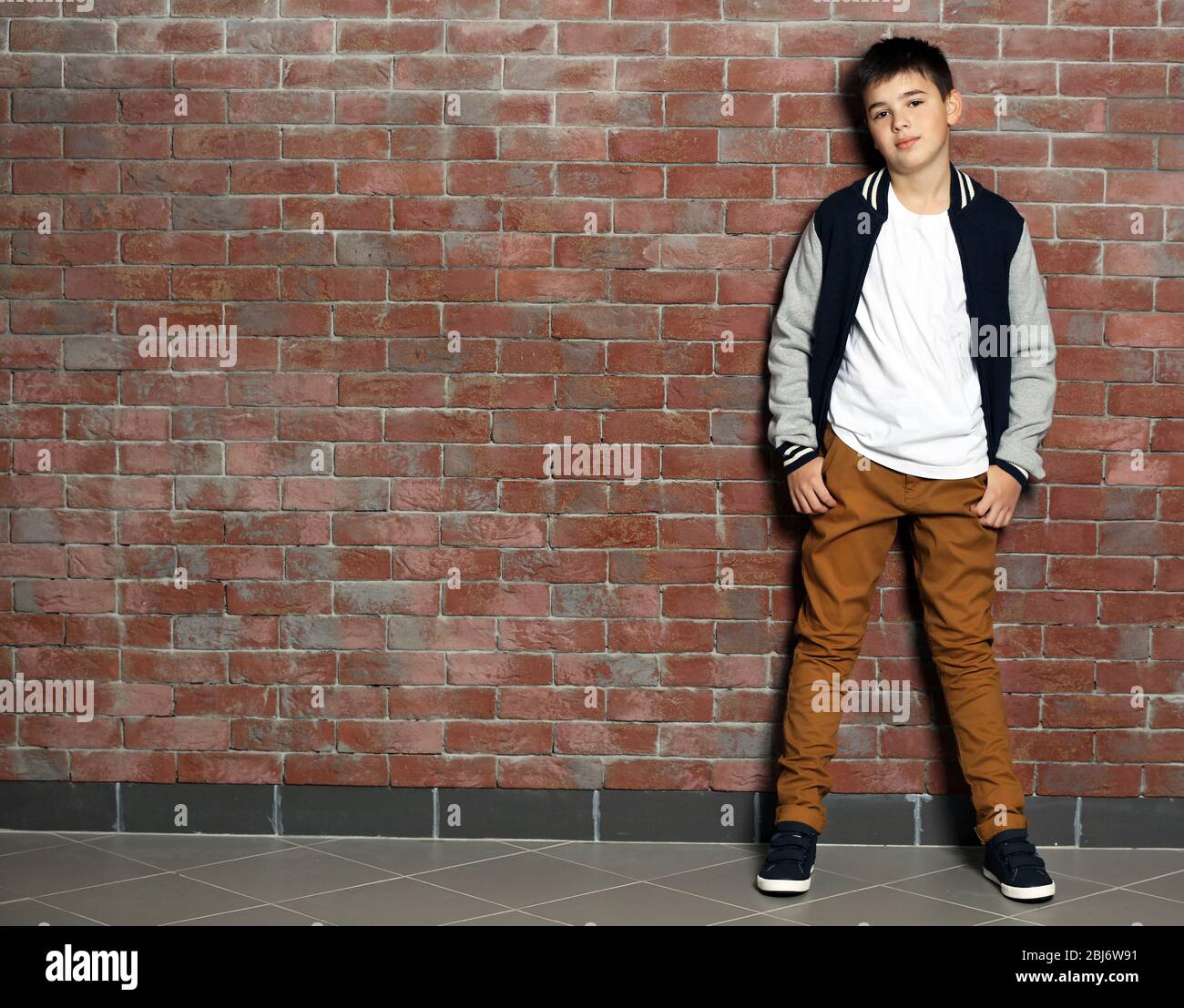 Cute little boy standing near brick wall Stock Photo - Alamy