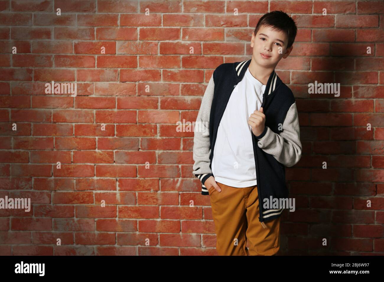 Cute little boy standing near brick wall Stock Photo - Alamy