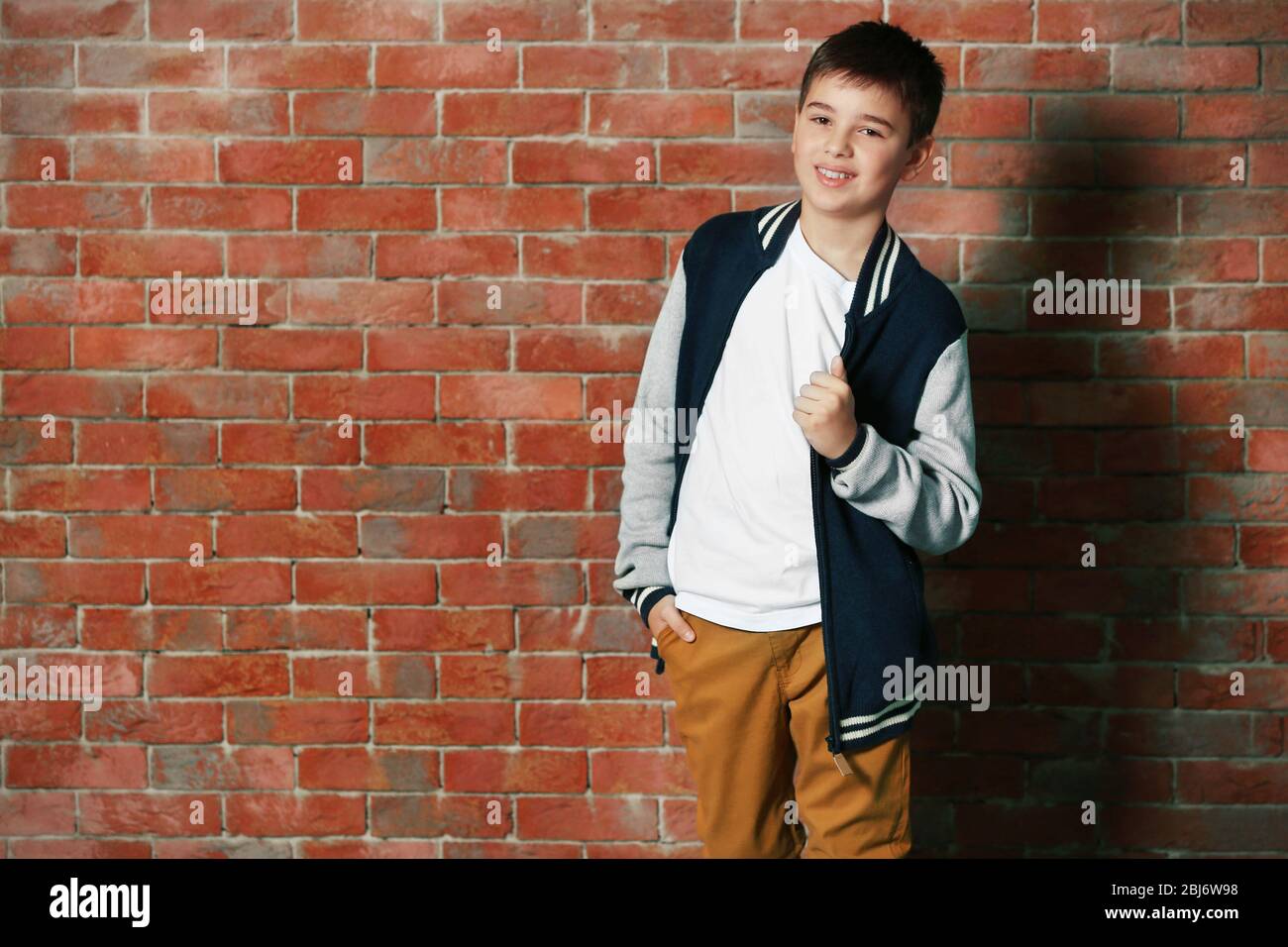 Cute little boy standing near brick wall Stock Photo - Alamy