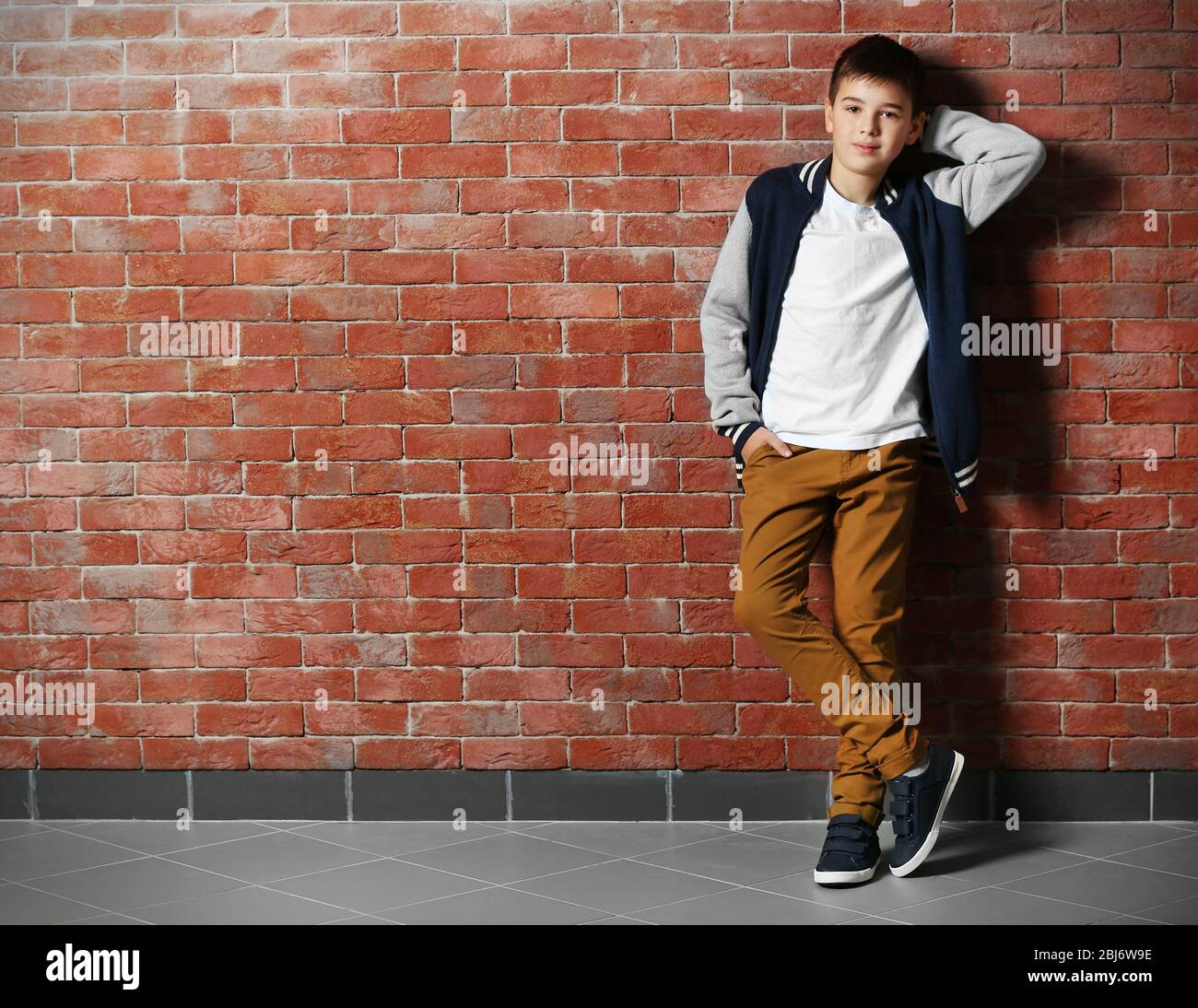 Cute little boy standing near brick wall Stock Photo - Alamy