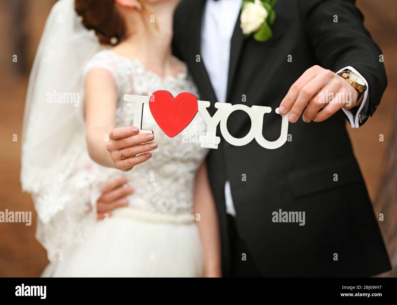 Happy wedding couple holding inscription with heart Stock Photo - Alamy