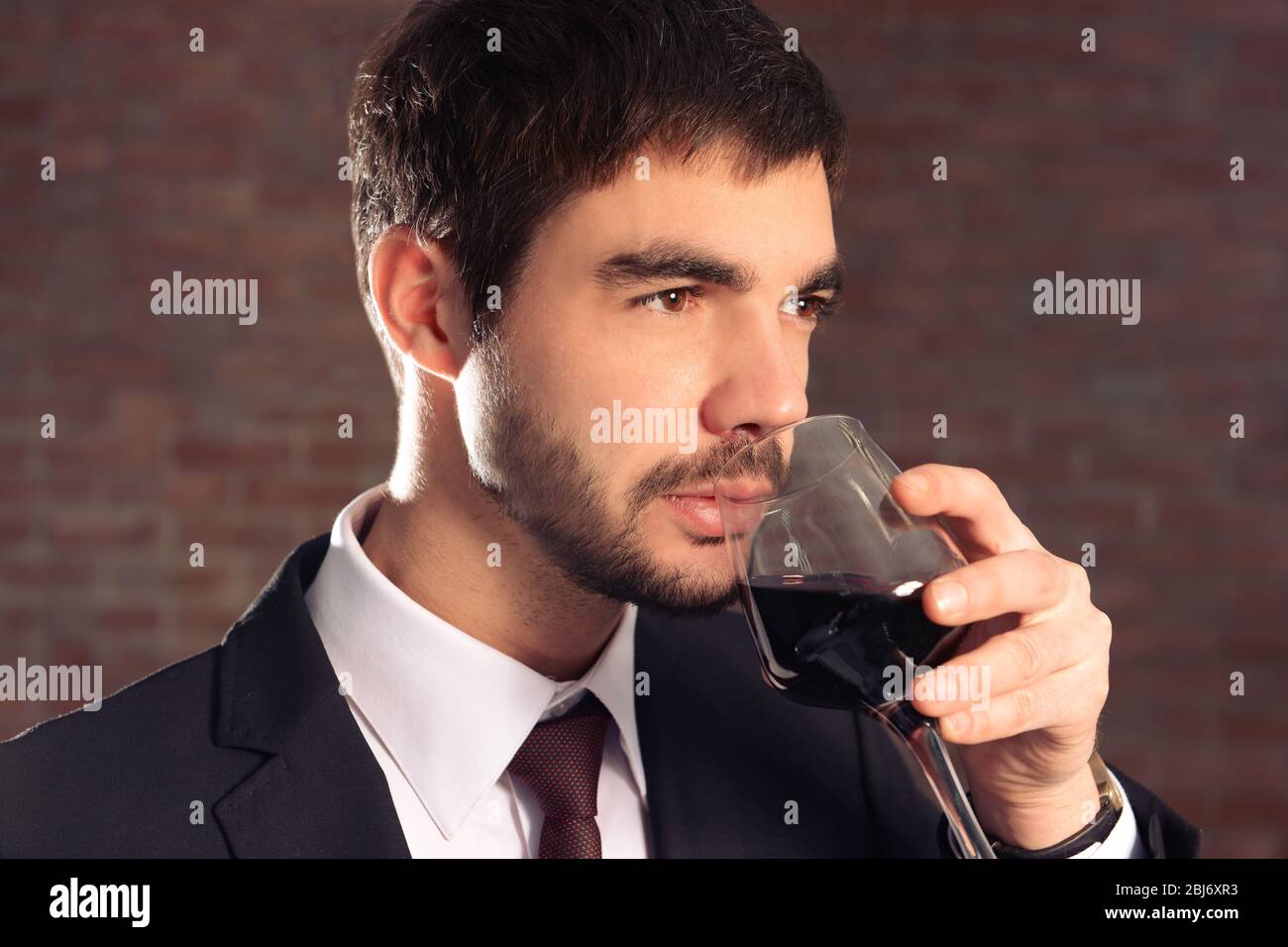 Man sniffing red wine in glass on brick wall background Stock Photo - Alamy