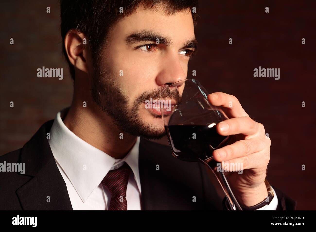 Man sniffing red wine in glass on brick wall background Stock Photo - Alamy