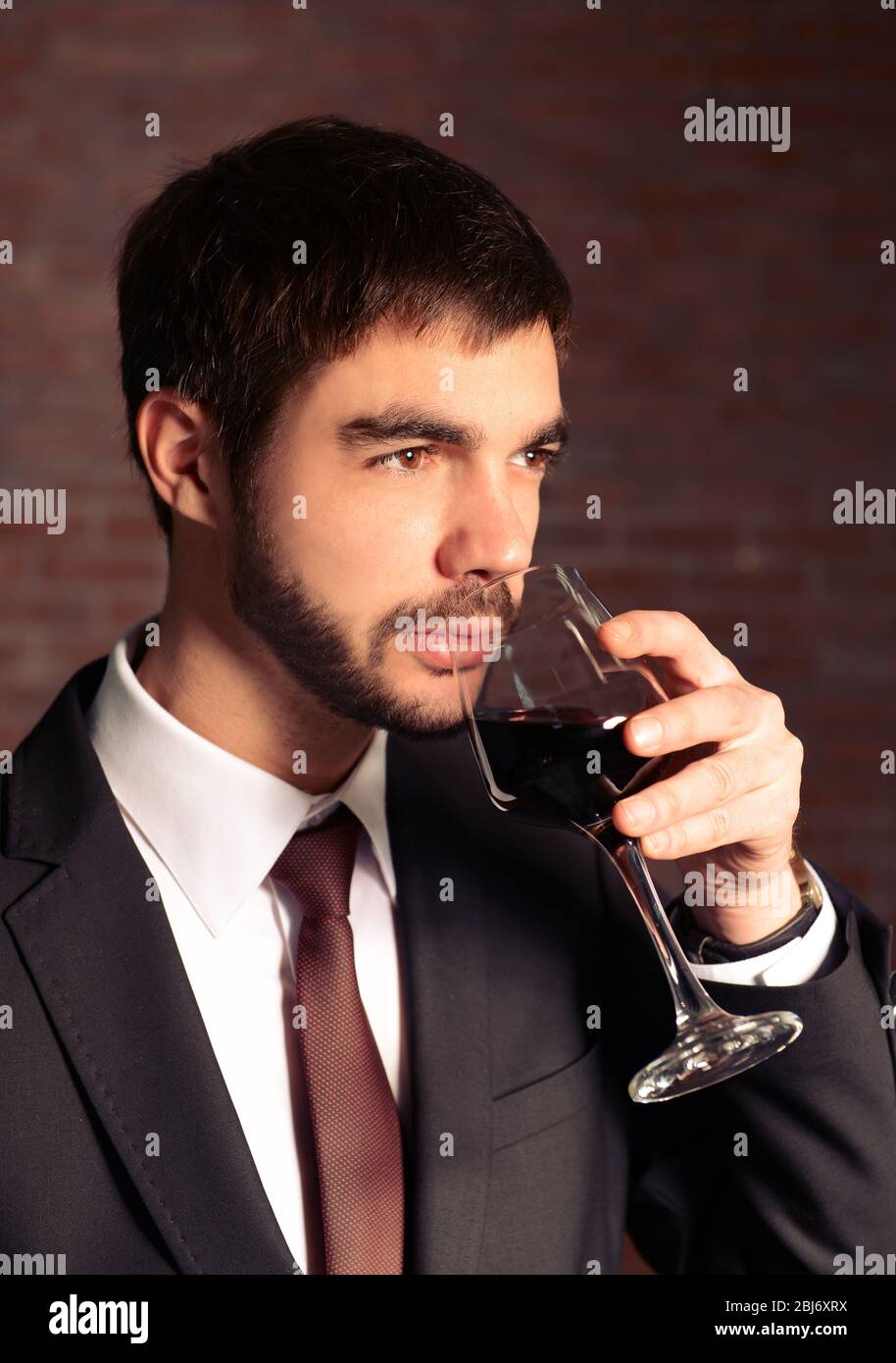 Man sniffing red wine in glass on brick wall background Stock Photo - Alamy