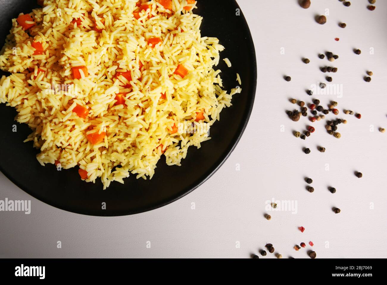 Stewed rice with a carrot on a black plate over white background Stock ...