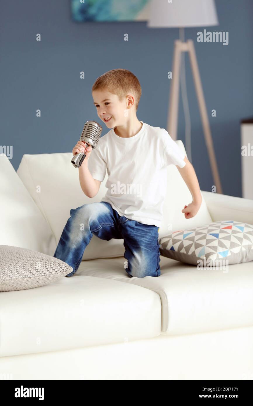 Little boy singing into the microphone on a sofa at home Stock Photo ...