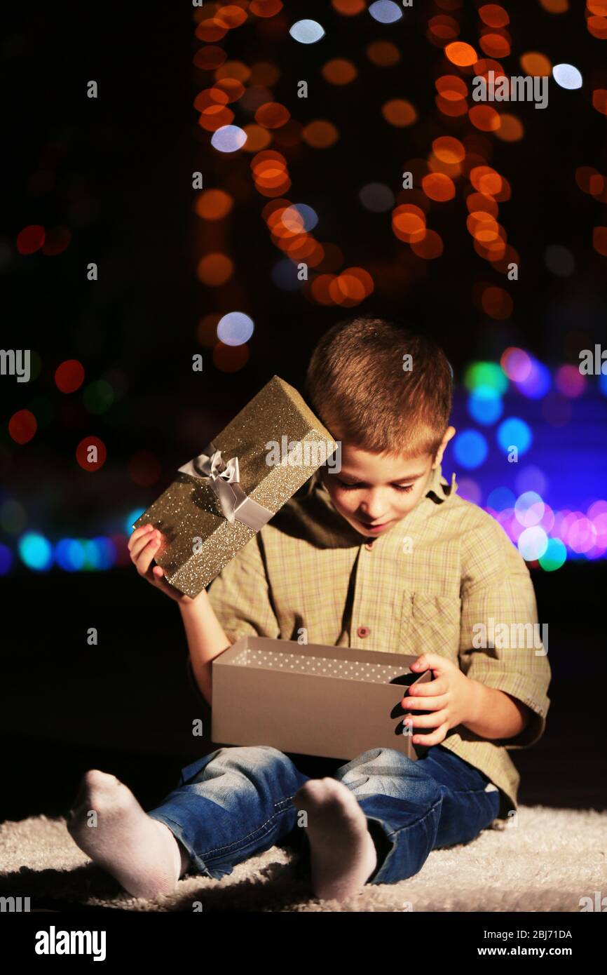 Little boy with gift box on a blurred dark background Stock Photo - Alamy