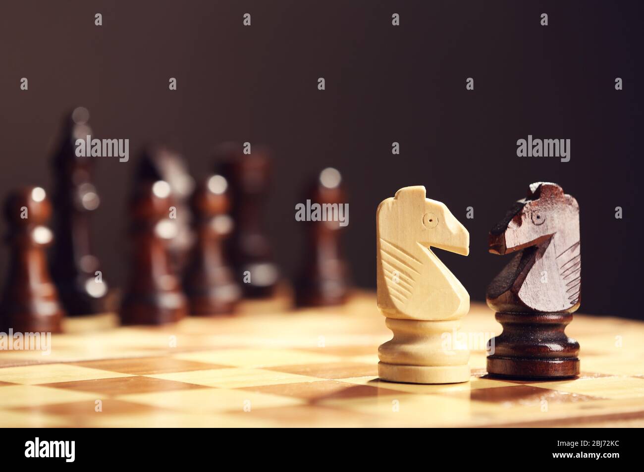 Chess pieces and game board on brown blurred background Stock Photo - Alamy