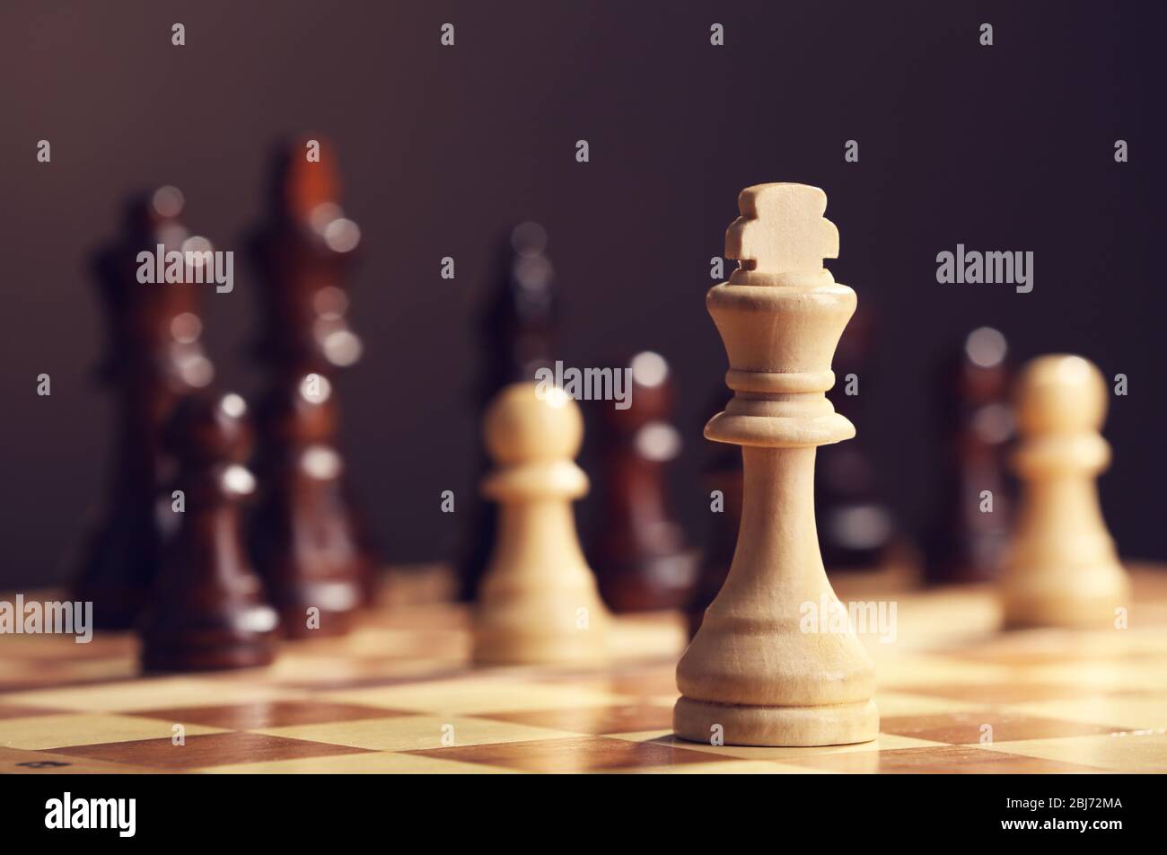 Chess pieces and game board on brown blurred background Stock Photo - Alamy