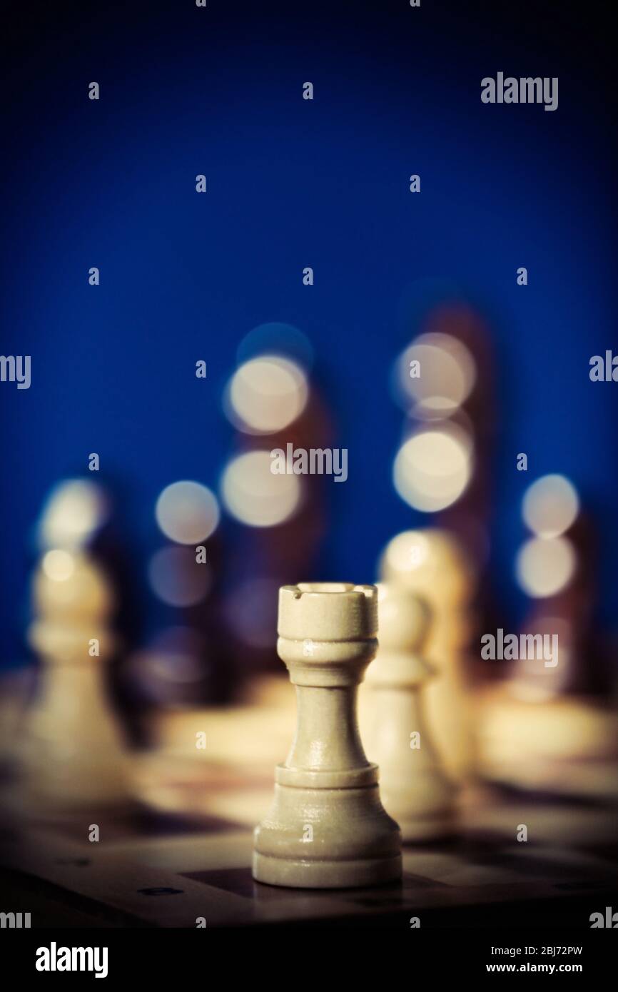 Chess pieces and game board on blue blurred background Stock Photo - Alamy