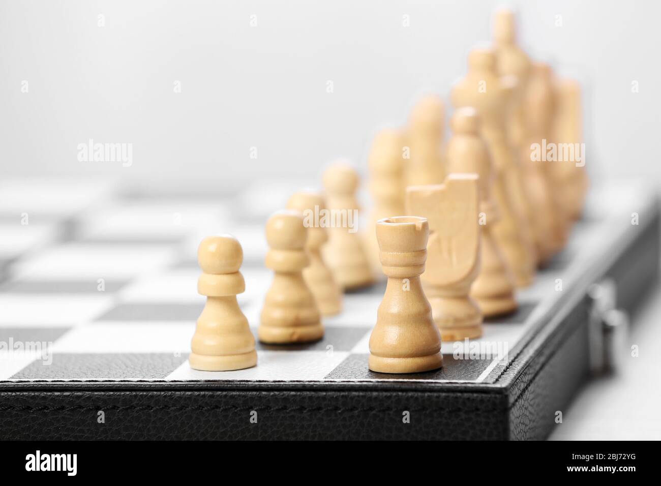 Chess pieces and game board on light blurred background Stock Photo - Alamy