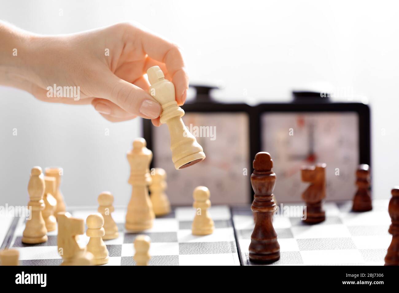 Female hand playing chess on light blurred background Stock Photo - Alamy