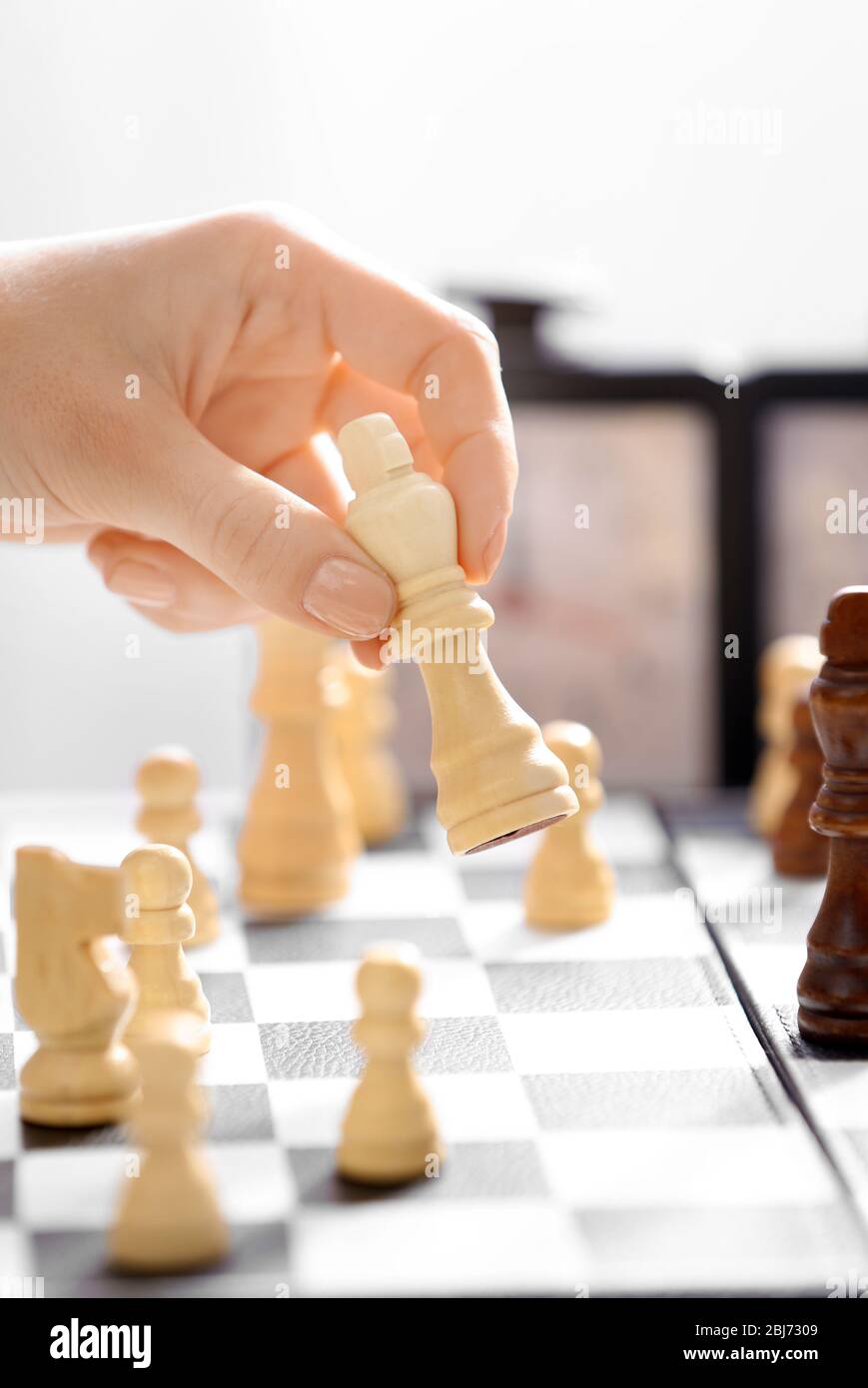 Female hand playing chess on light blurred background Stock Photo - Alamy