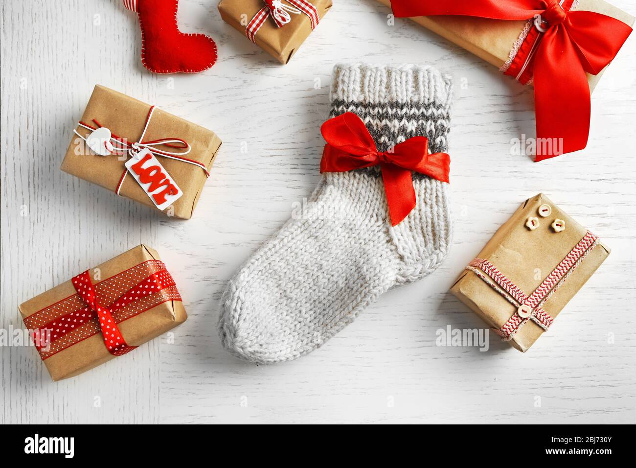Pair of knitted socks with wrapped gifts on light table Stock Photo - Alamy