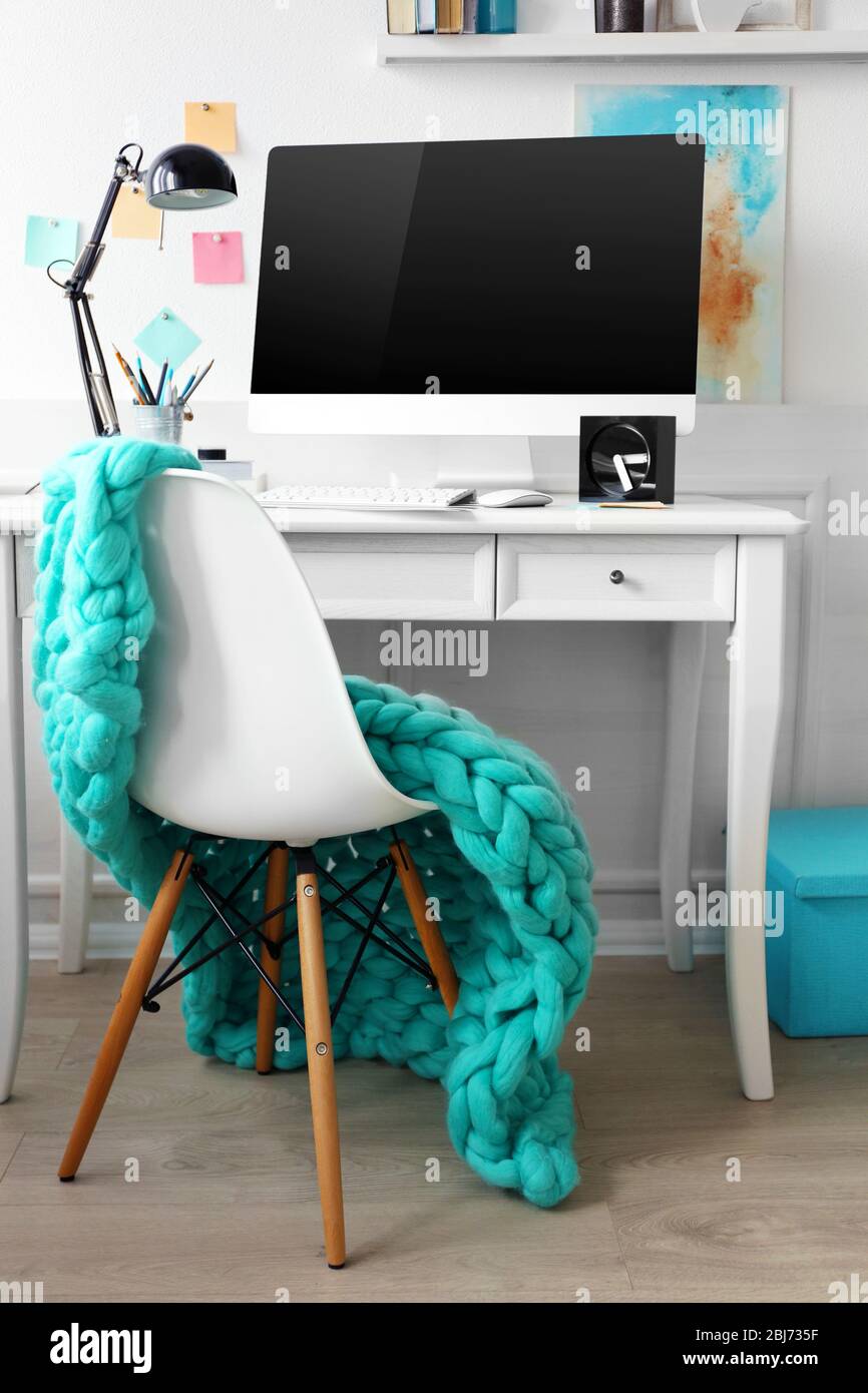 Modern wide screen monitor on white table and chair in room interior ...