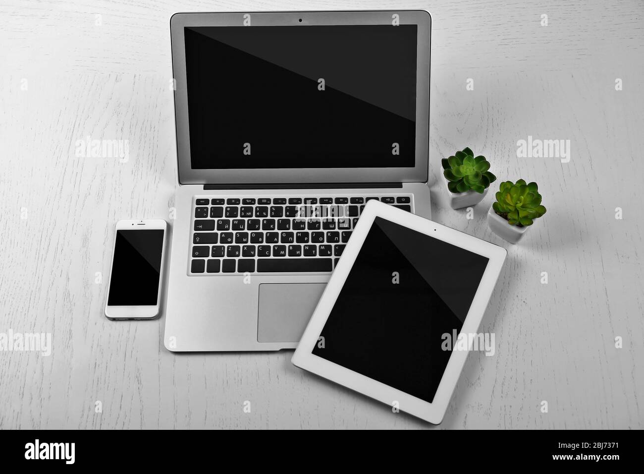 Different modern devices with green plants on light table Stock Photo ...