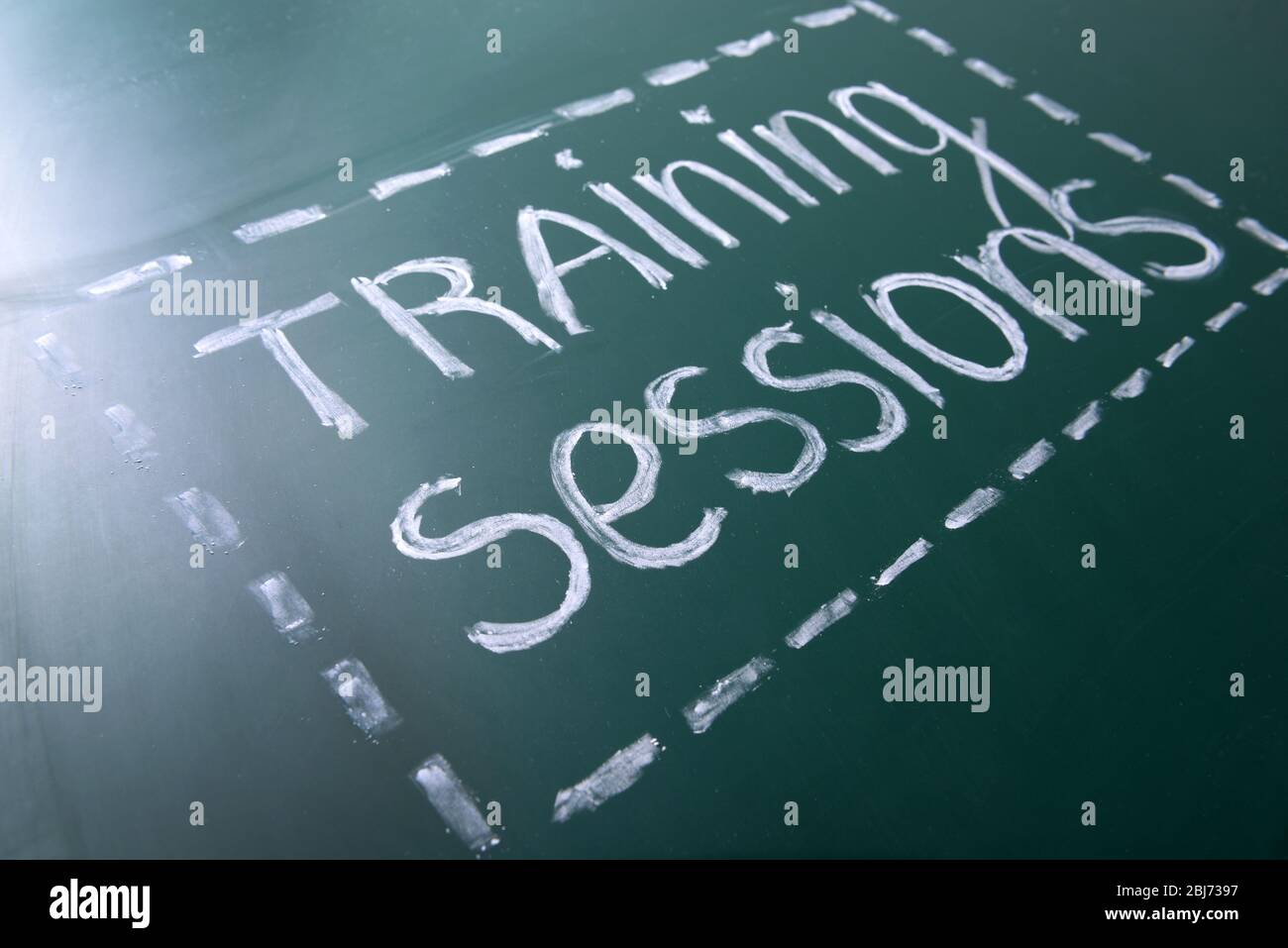 Training sessions inscription written with white chalk on blackboard ...