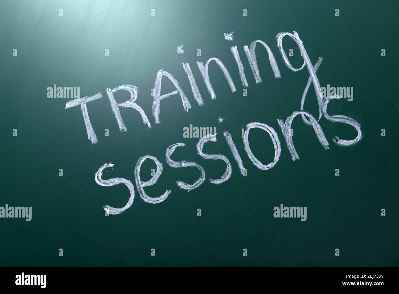 Training sessions inscription written with white chalk on blackboard ...