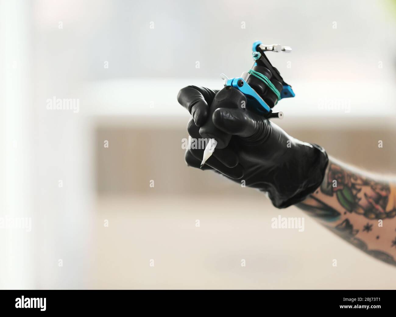 Man's hand holding tattoo machine on blurred background Stock Photo - Alamy