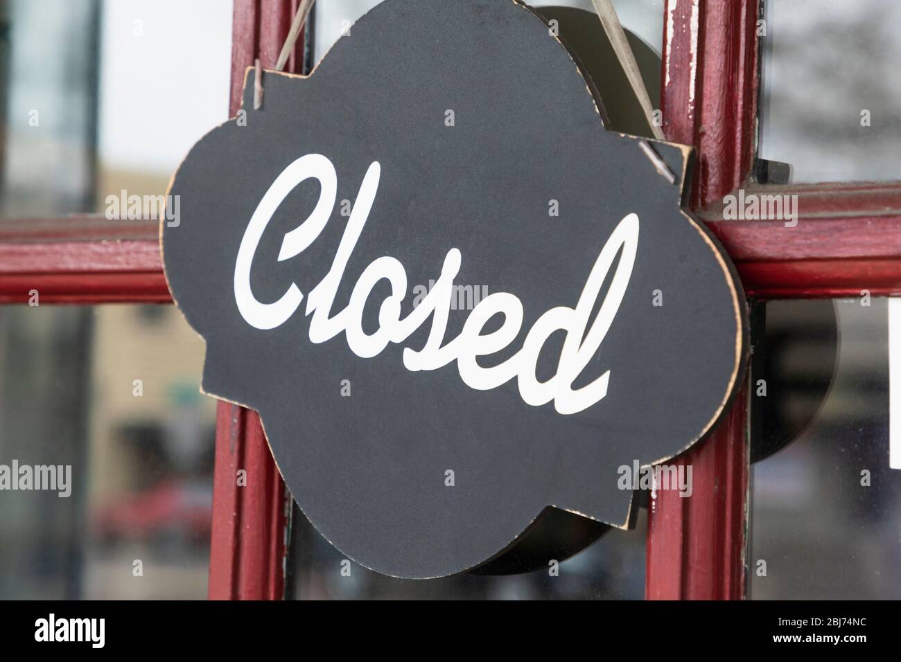 Closed sign hangs prominently on the door of a local shop on a quiet ...