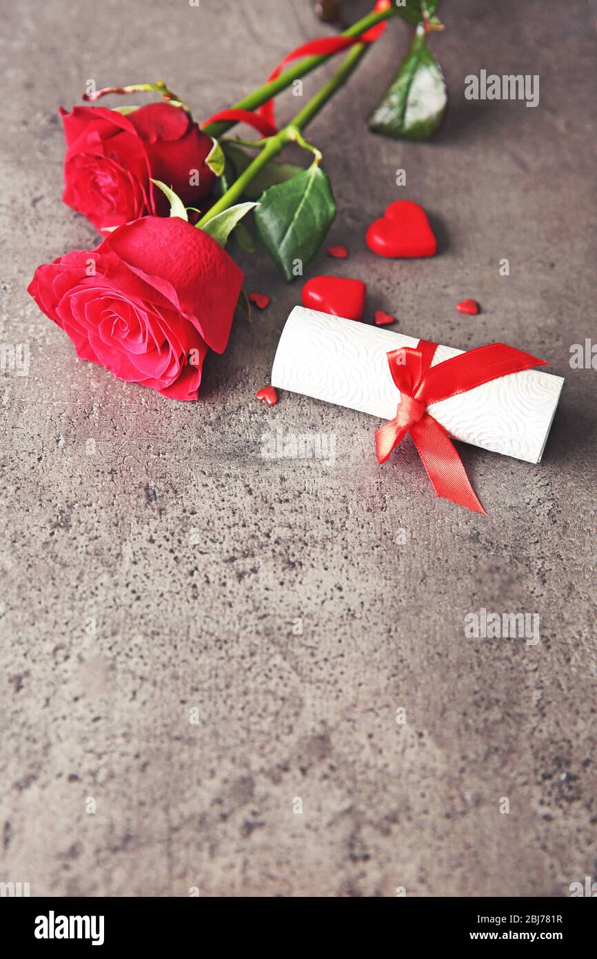 Red roses with rolled present card on grey textured background Stock ...