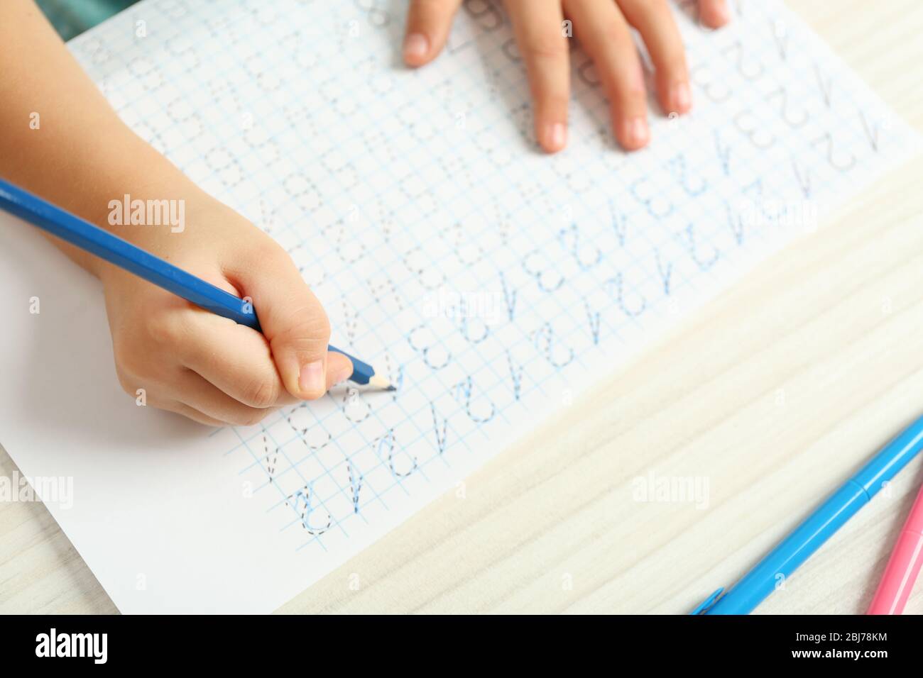 Schoolkid learns to write on sheet of paper, closeup Stock Photo - Alamy