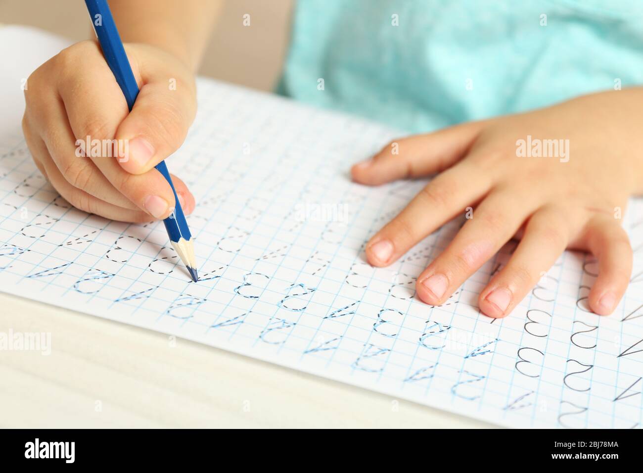 Schoolkid learns to write on sheet of paper, closeup Stock Photo - Alamy