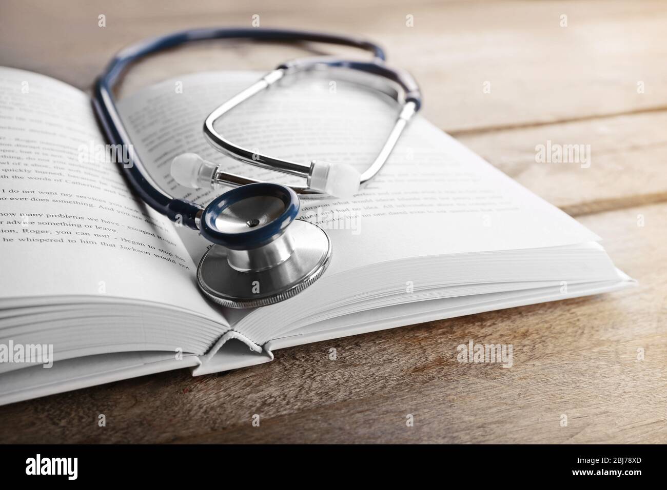 Stethoscope with open book on wooden background. Medical literature ...