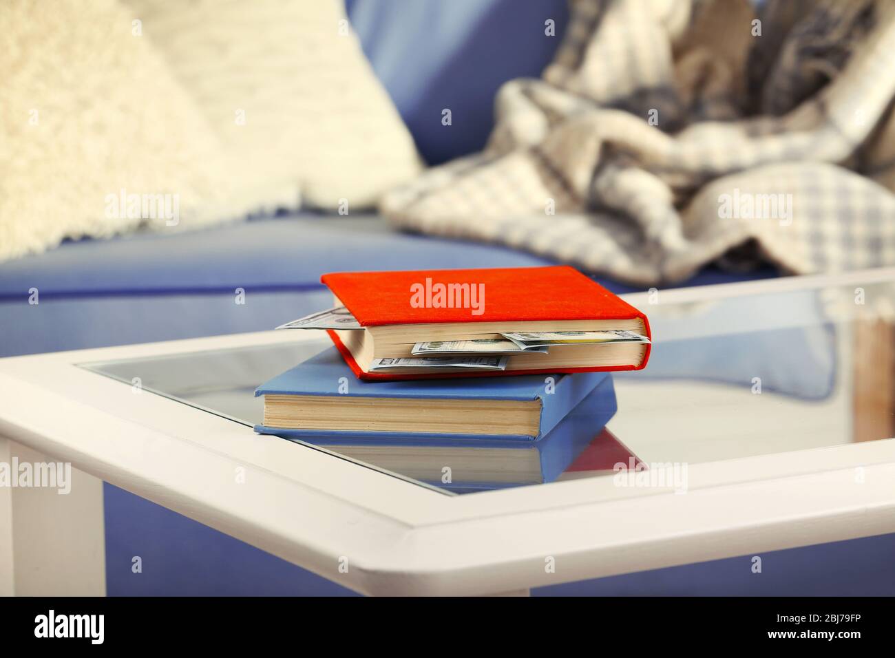 Red and blue books with hidden dollar banknotes on glass table Stock ...