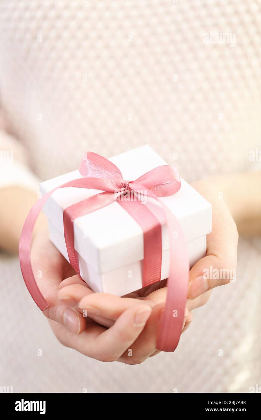 Female hands holding beautiful small gift wrapped with satin ribbon ...