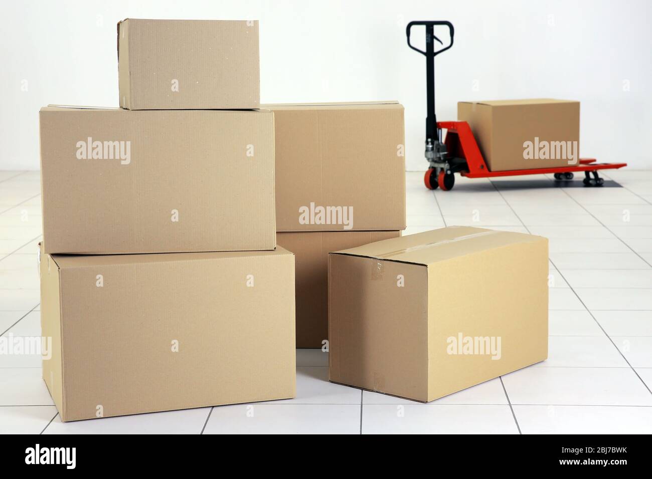 Stack of carton boxes and manual pallet truck indoors Stock Photo - Alamy