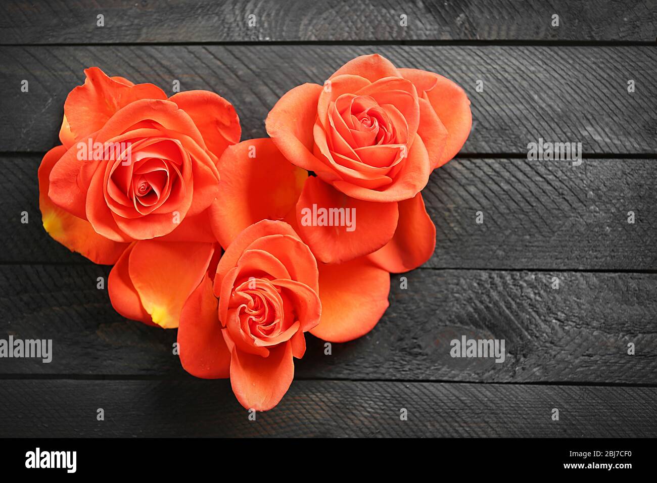 Fresh red roses buds in shape of heart on wooden background Stock Photo ...