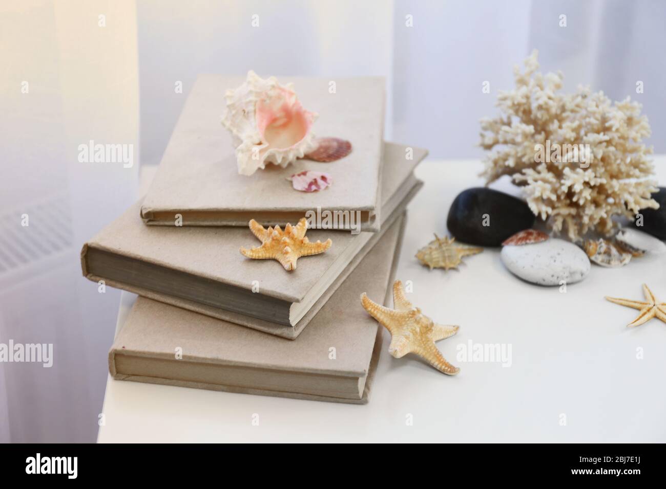 Books and seashells on the table in the room Stock Photo - Alamy