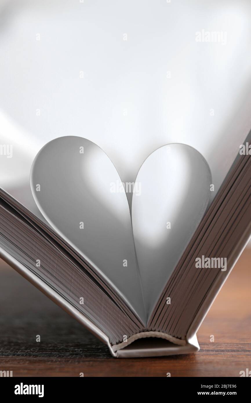 Heart from book pages on blurred background Stock Photo - Alamy