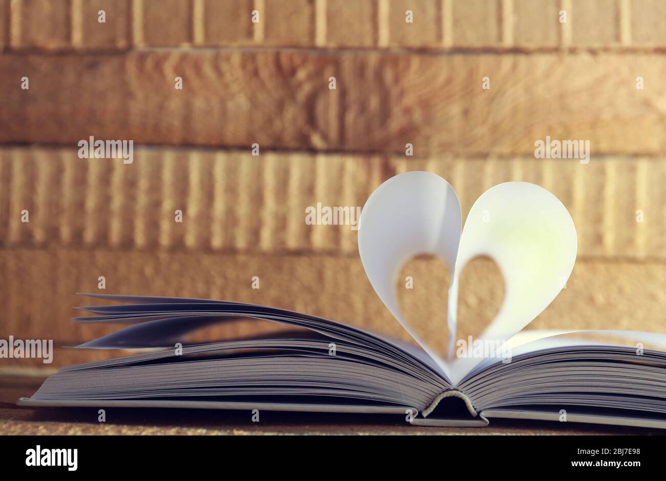 Heart from book pages on wooden blurred background Stock Photo - Alamy