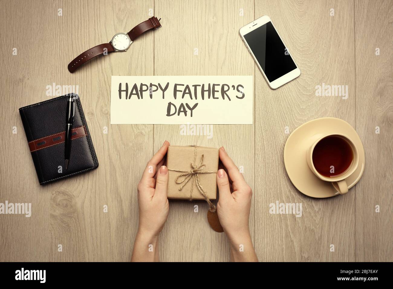 Happy Father's Day inscription with gifts and female hands on wooden ...