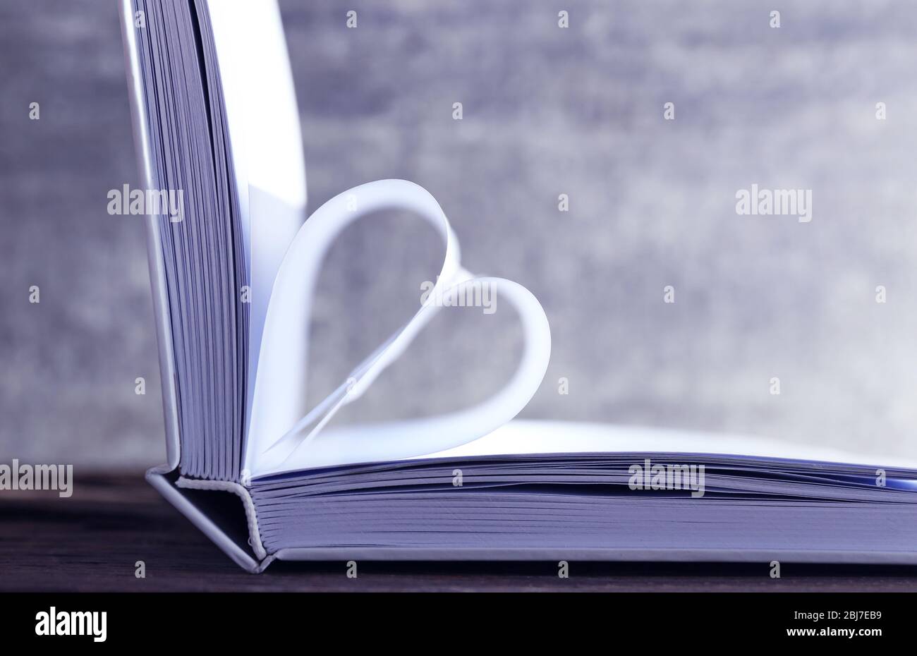 Heart from book pages on grey blurred background Stock Photo - Alamy