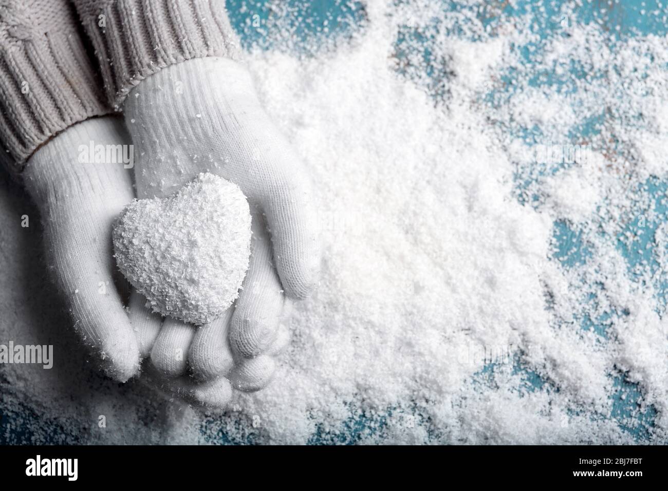 Female hands in mittens with heart on snow background Stock Photo - Alamy