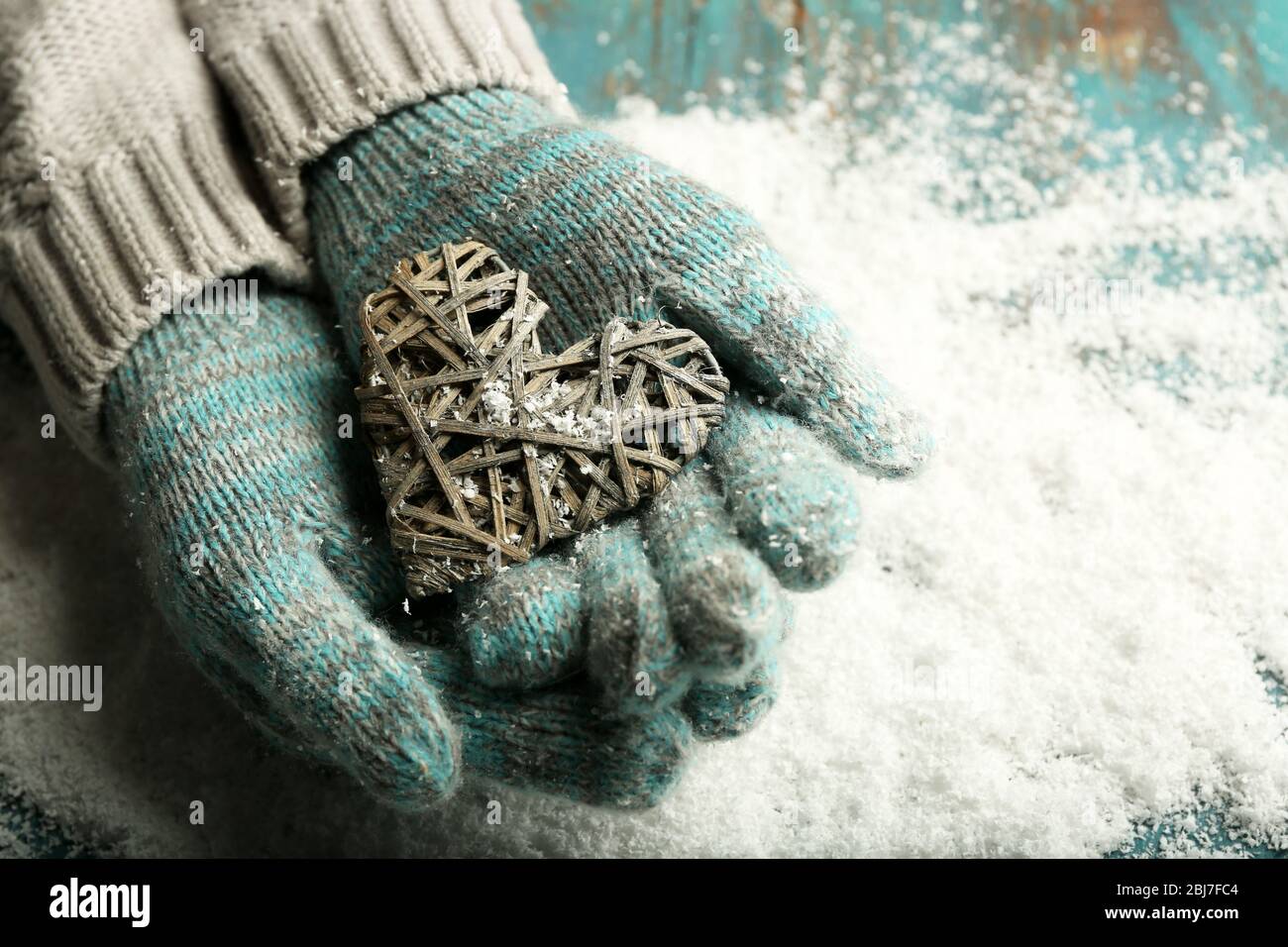 Female hands in mittens with heart on snow background Stock Photo - Alamy