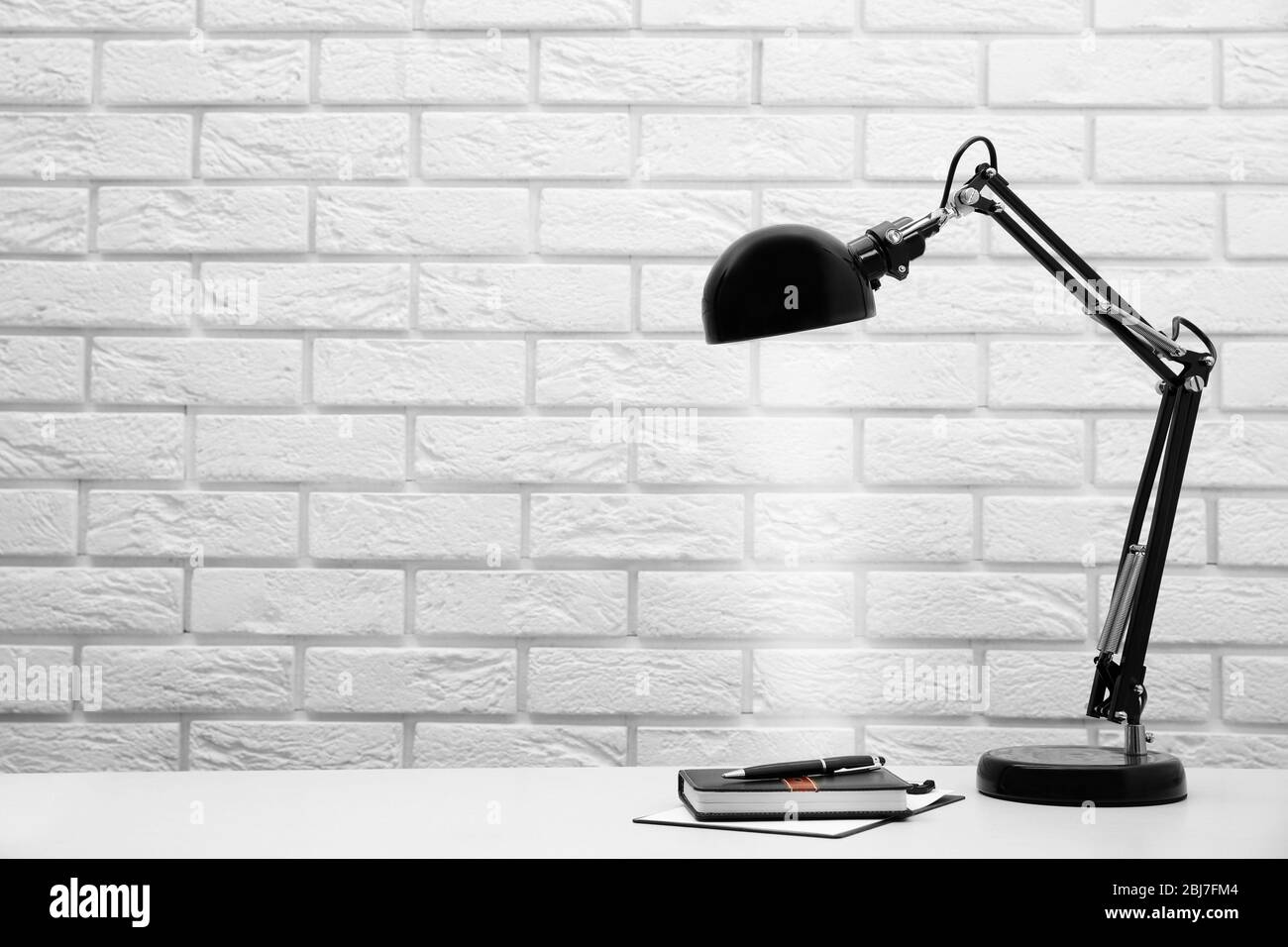 Lamp on the desk on white brick wall background Stock Photo - Alamy