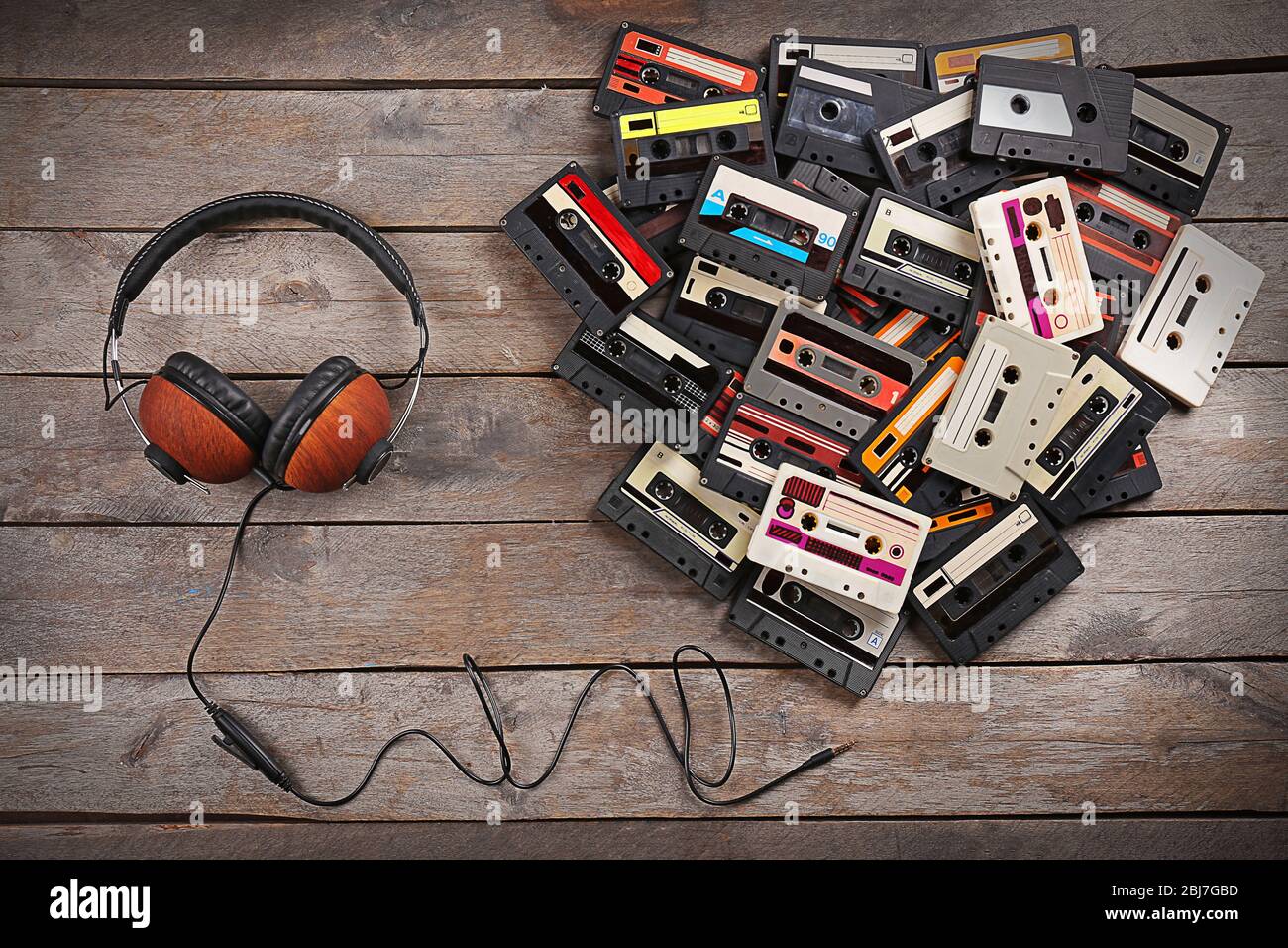 Group of audio cassettes with headphones on wooden table background ...
