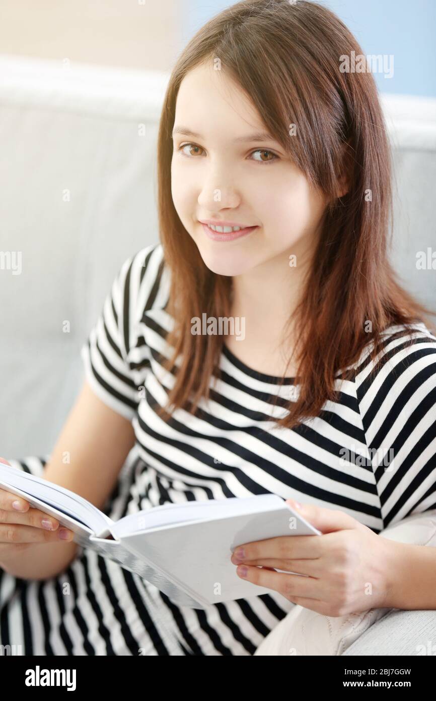 Beautiful girl reading book on sofa, indoor Stock Photo - Alamy