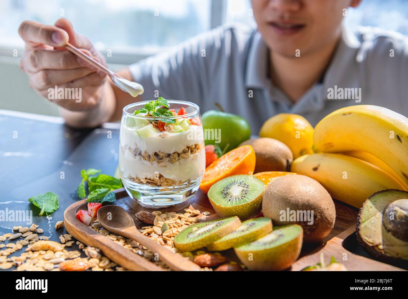 Close up of many fruit yogurt with granola and man scooping hand on ...