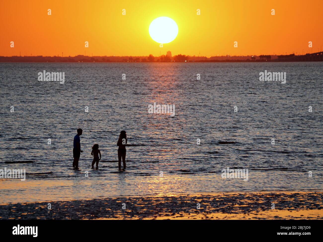 Silhouette of visitors in the shallow water during sunset at Rocky ...