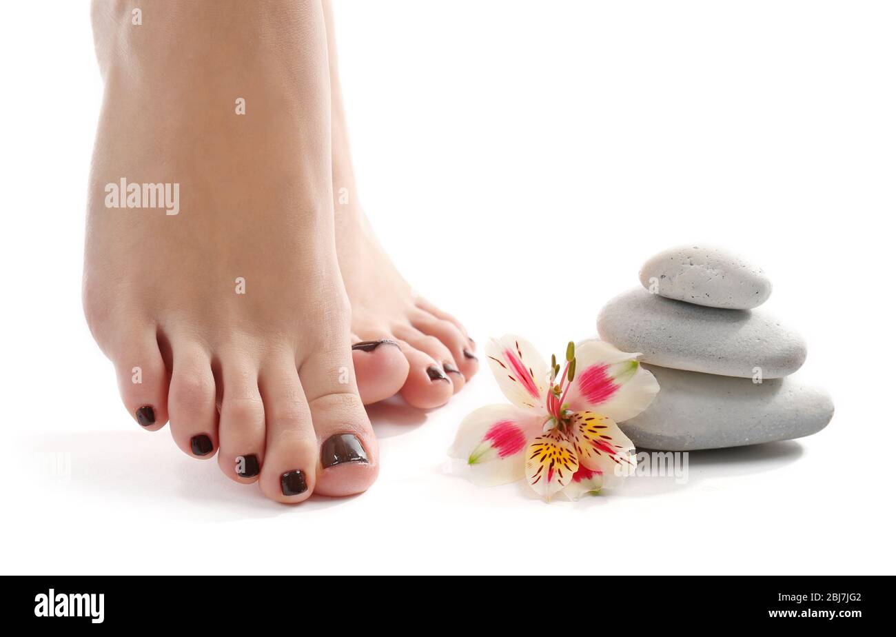 Manicured female feet with spa stones and flowers isolated on white ...